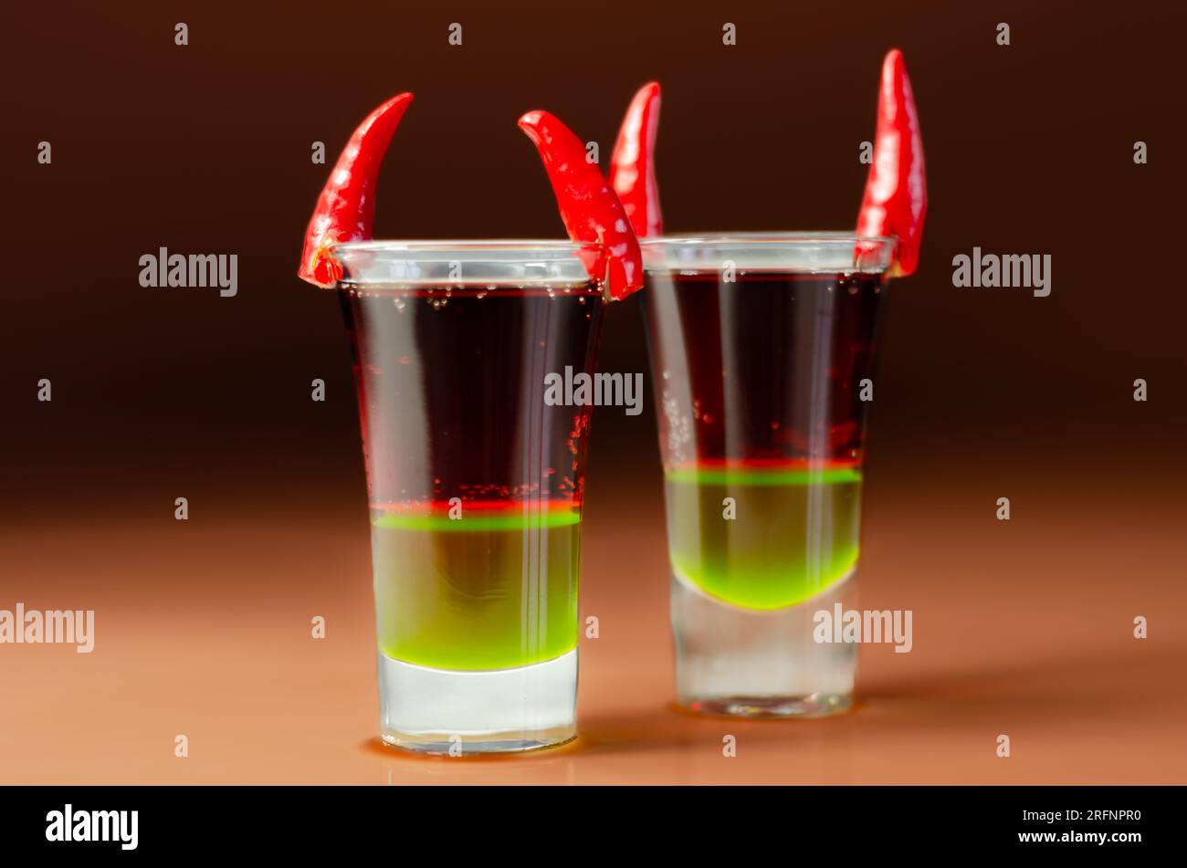 Layered drink shot prepared with vodka, green liquor, grenadine and ...