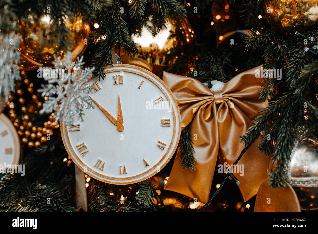 Christmas clock hanging on the Christmas tree with golden bow. New Year ...