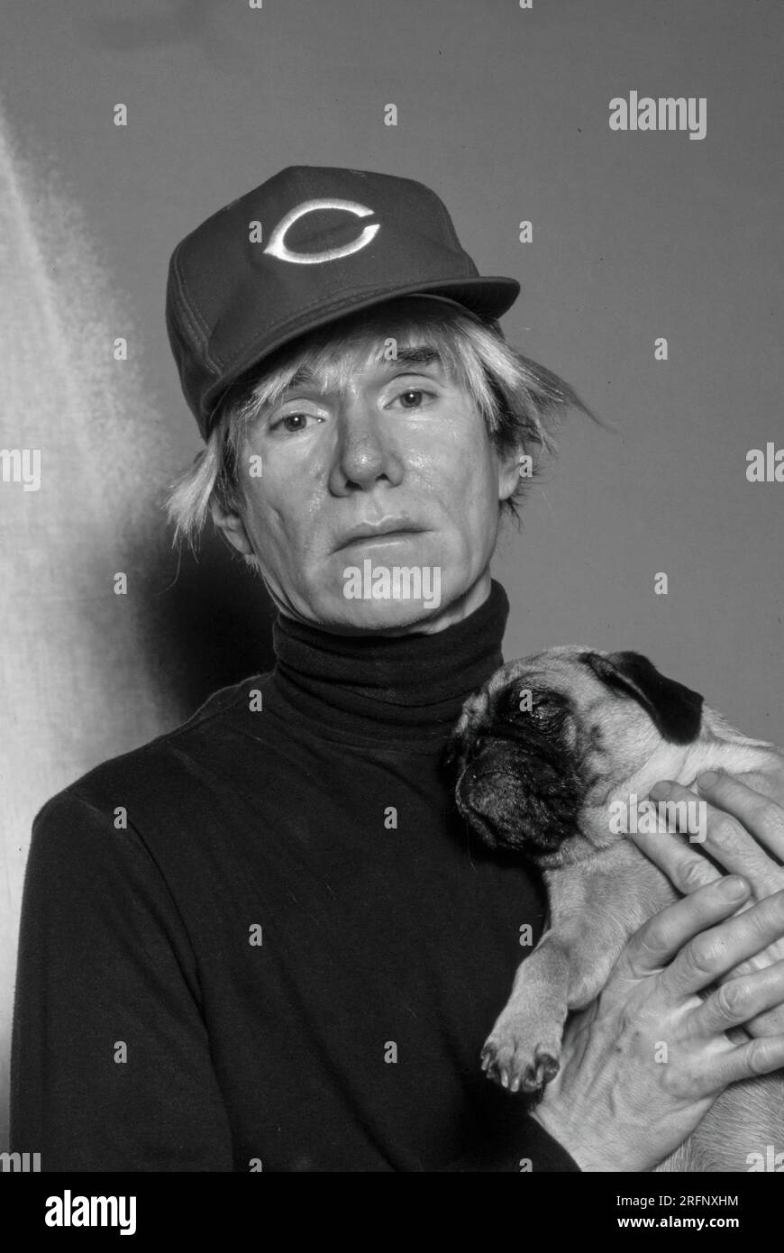 Andy Warhol poses wearing Cincinnati Reds baseball cap while holding ...