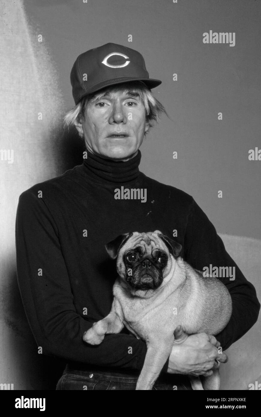 Andy Warhol poses wearing Cincinnati Reds baseball cap while holding ...