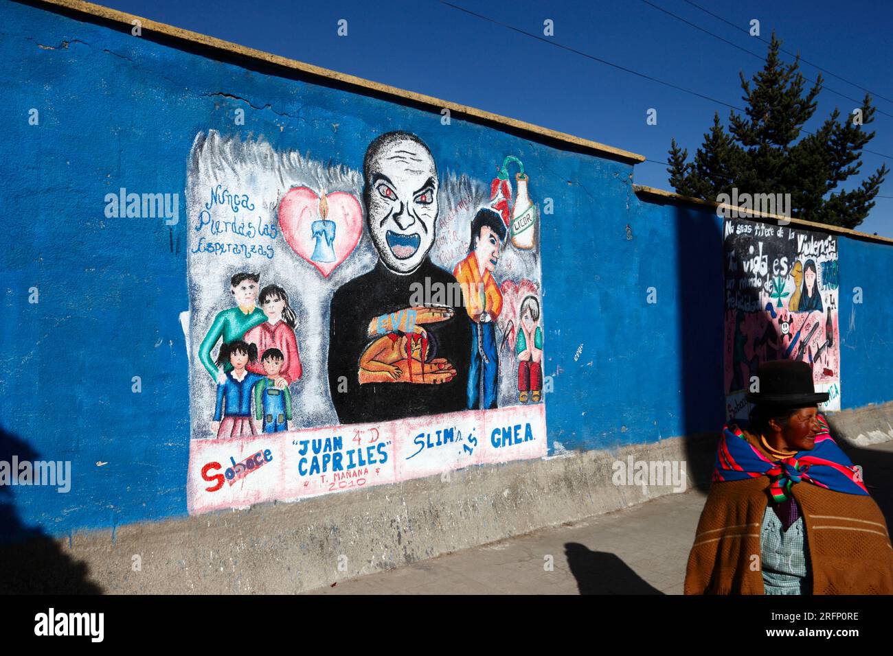Native Aymara woman walking past a mural that is part of a campaign to ...
