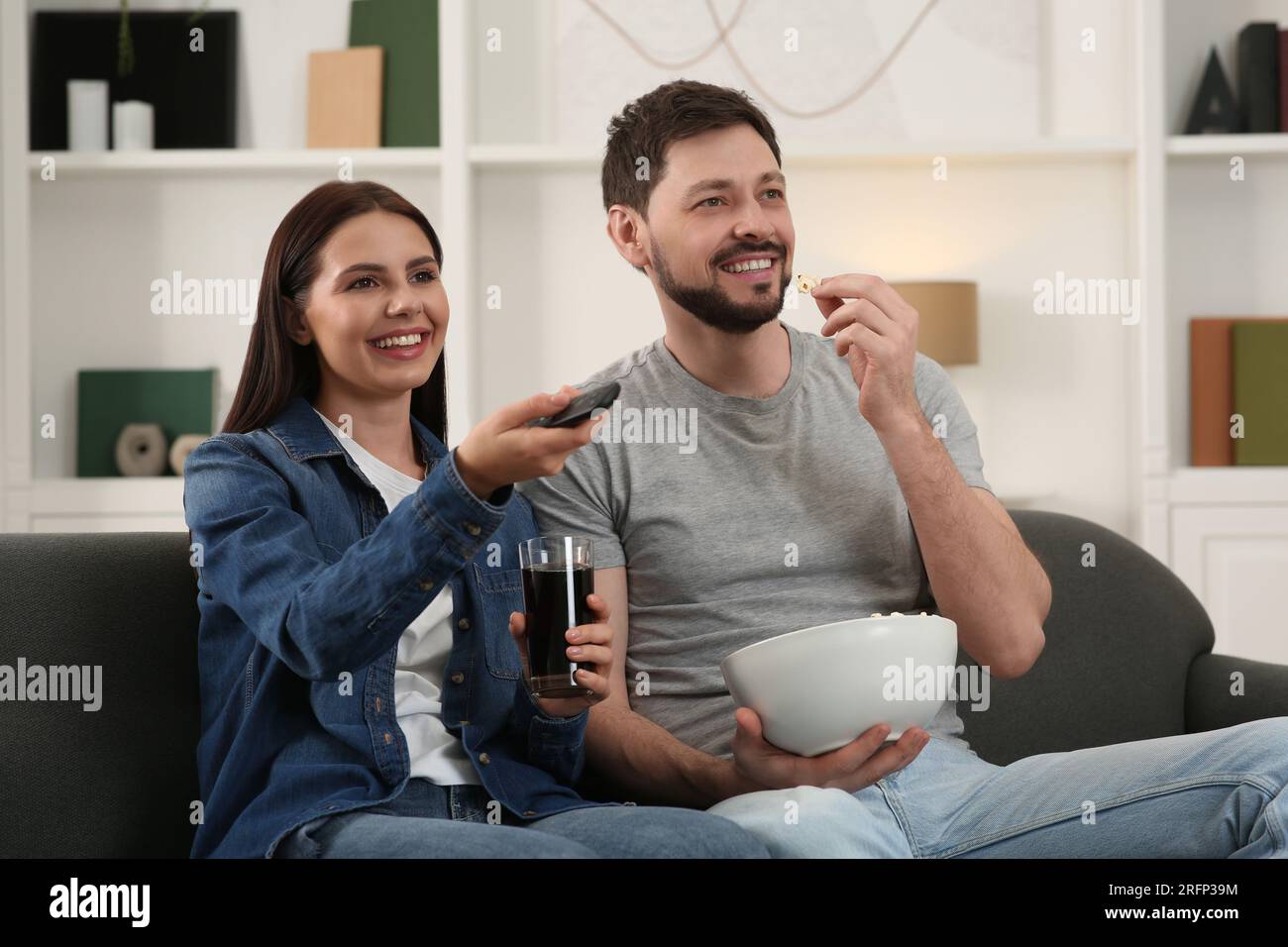 Happy couple watching show at home. Woman changing TV channels with ...