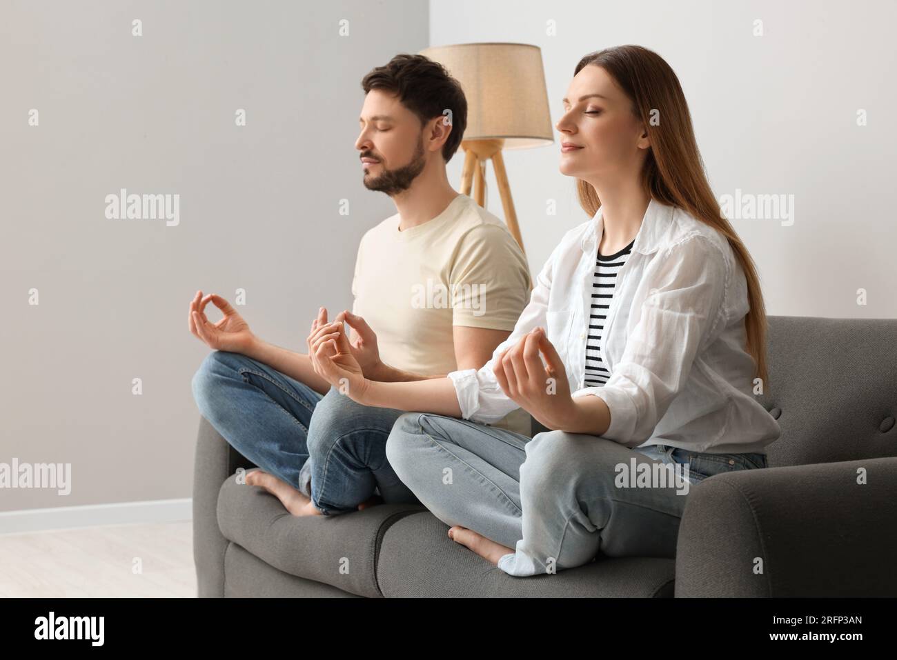 Couple meditating together on sofa at home. Harmony and zen Stock Photo ...