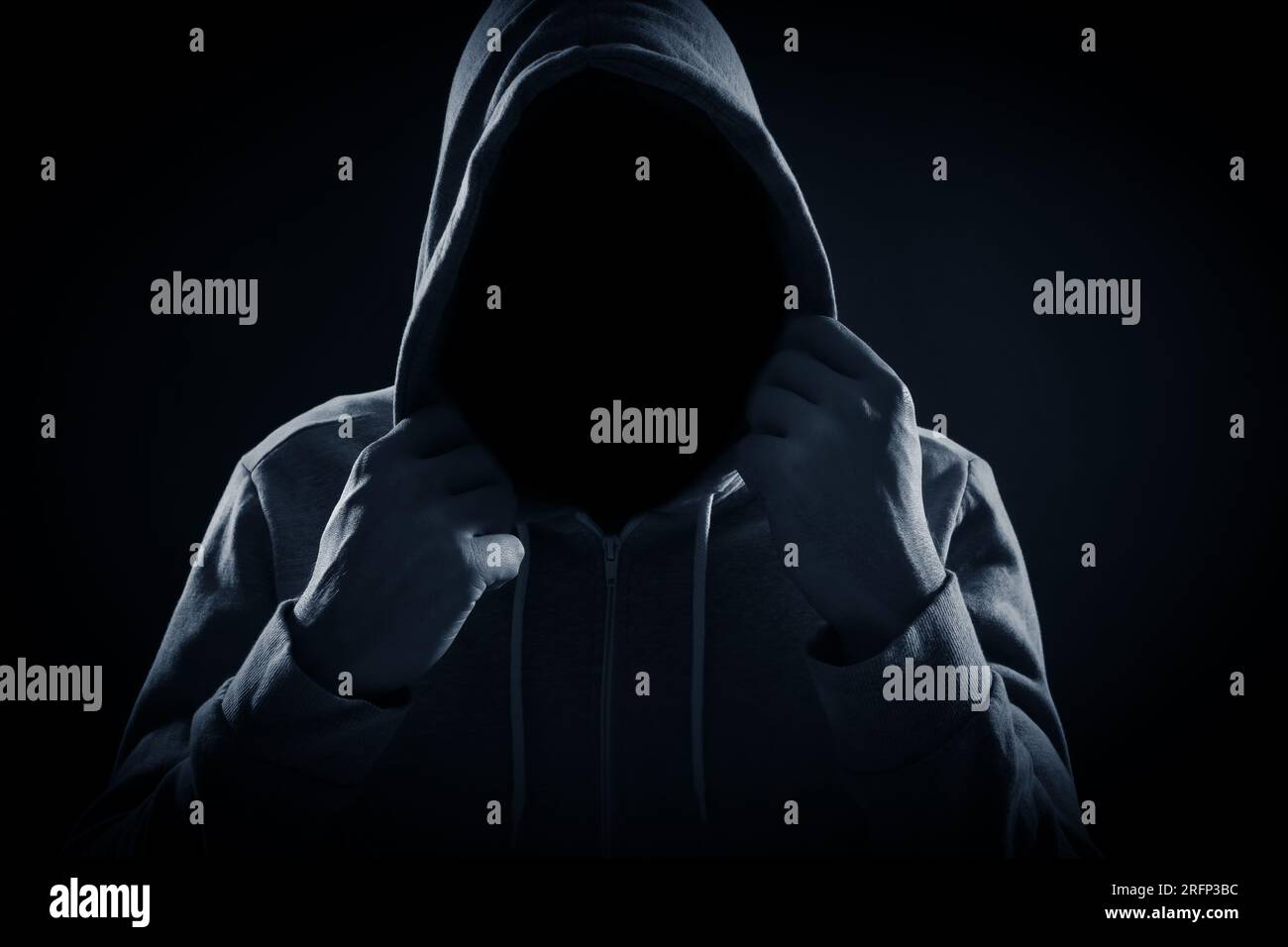 Anonymous man in hood on black background Stock Photo - Alamy