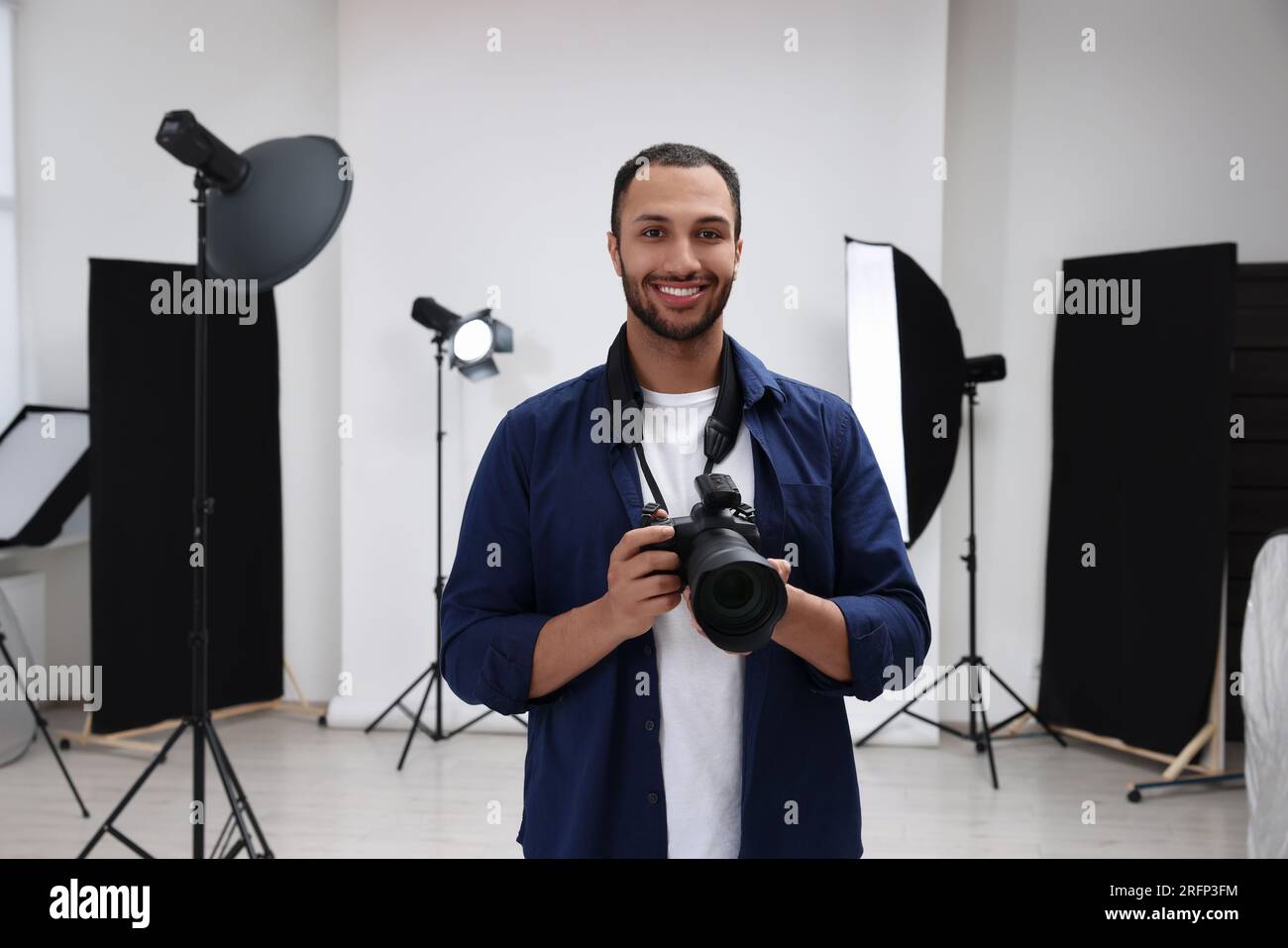 Young professional photographer with camera in modern photo studio ...
