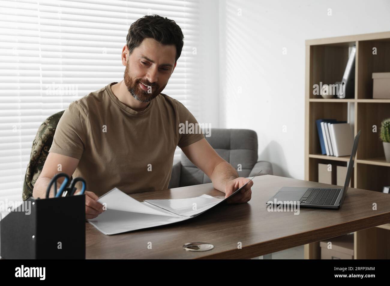 Happy soldier working with documents at wooden table indoors. Military ...