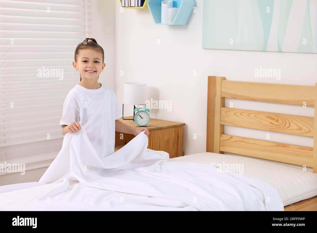 Cute girl changing bed linens in children room Stock Photo - Alamy