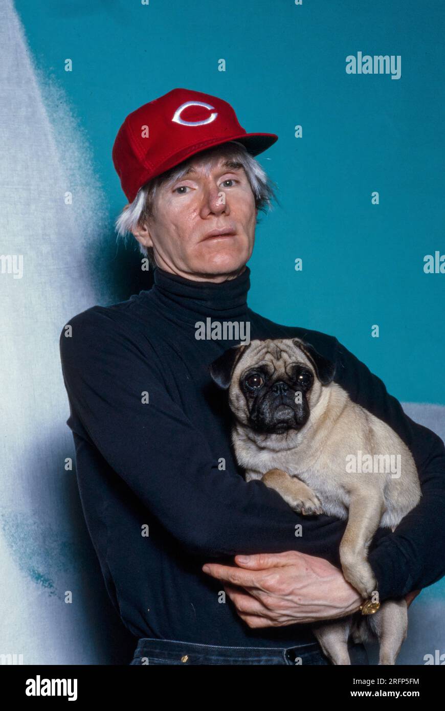 Andy Warhol poses wearing Cincinnati Reds baseball cap while holding ...