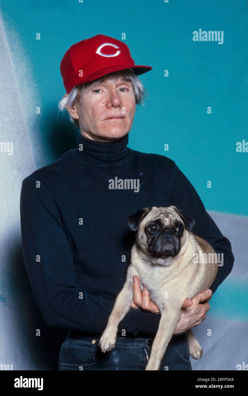 Andy Warhol poses wearing Cincinnati Reds baseball cap while holding ...