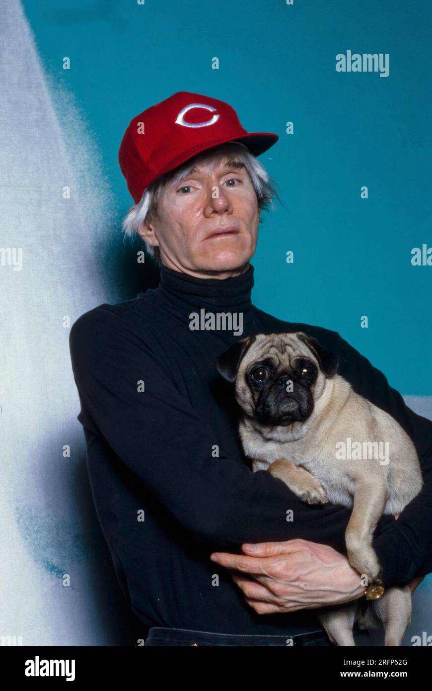 Andy Warhol poses wearing Cincinnati Reds baseball cap while holding ...