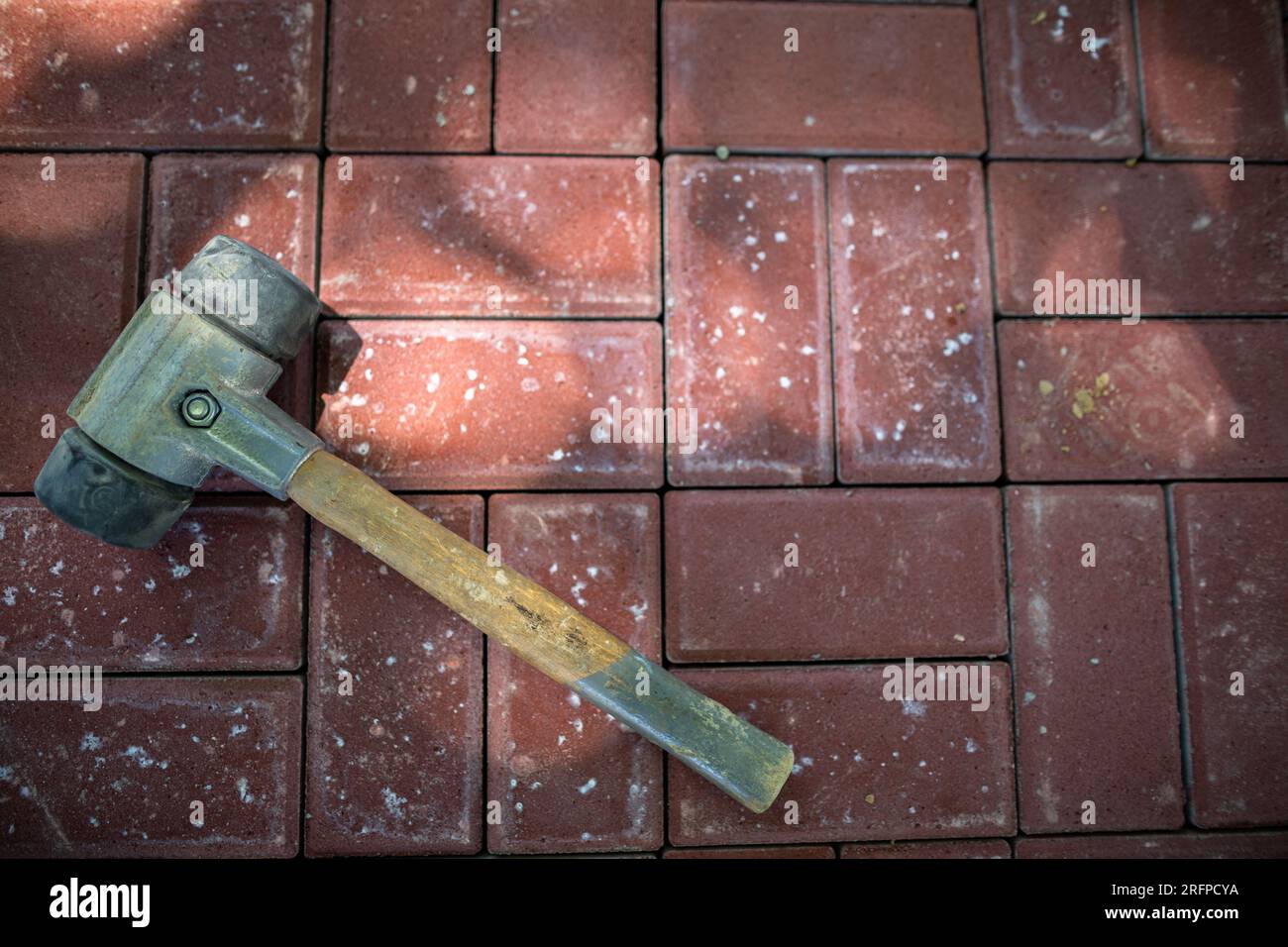 A hammer with rubber tips used in paving works lies on the paving ...