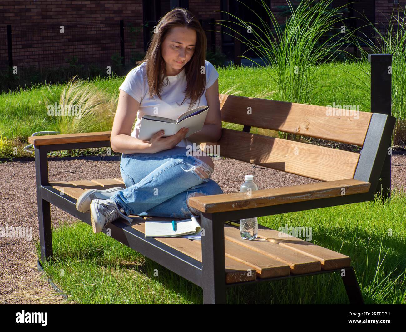 Female student studying on bench at campus Stock Photo - Alamy