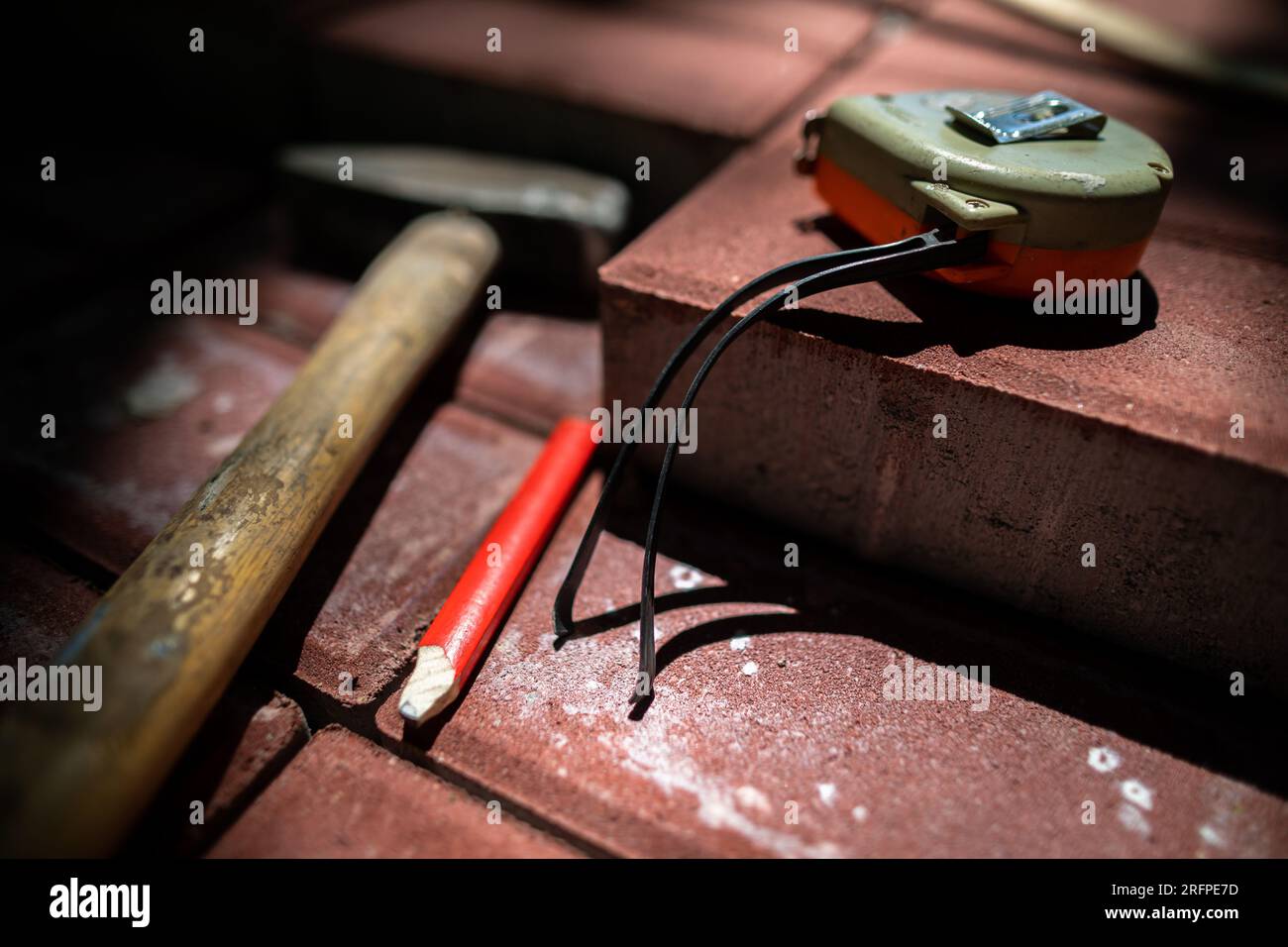 A hammer and a pencil and a tape measure lie on the cobblestones Stock ...