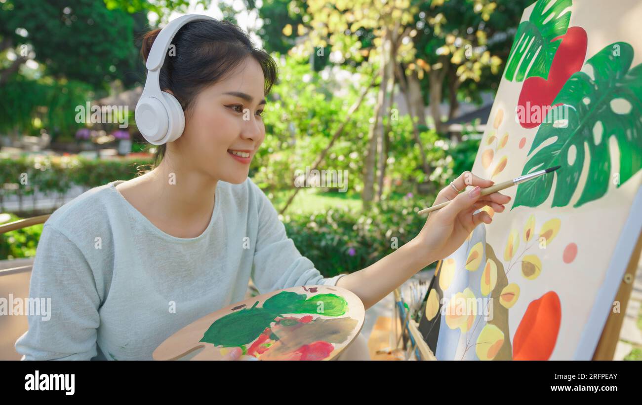 Outdoor activity concept, Female artist listening music while painting ...