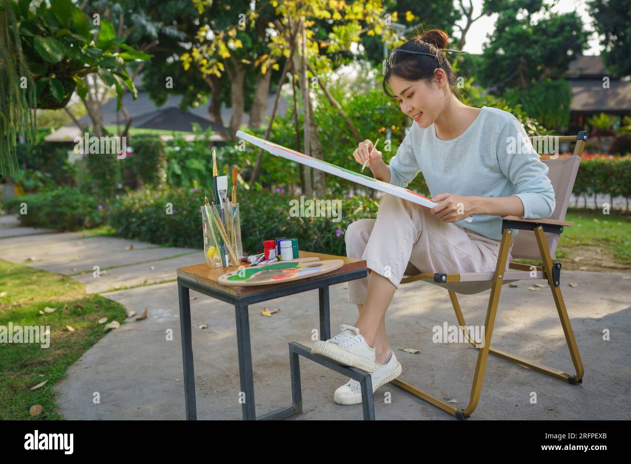 Outdoor activity concept, Female artist sits in park and painting ...