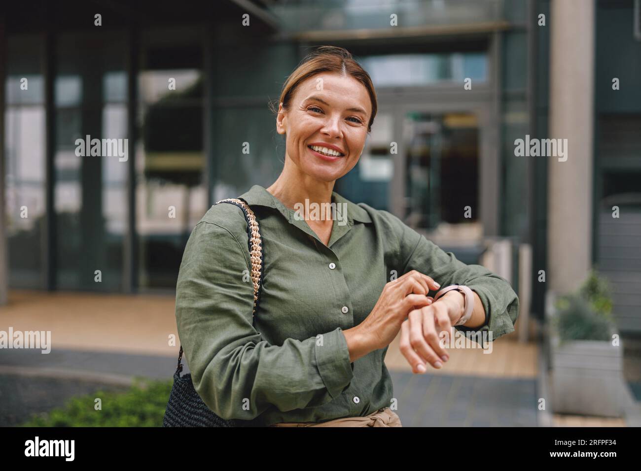 Woman freelancer looking on her wrist watch standing on modern office ...