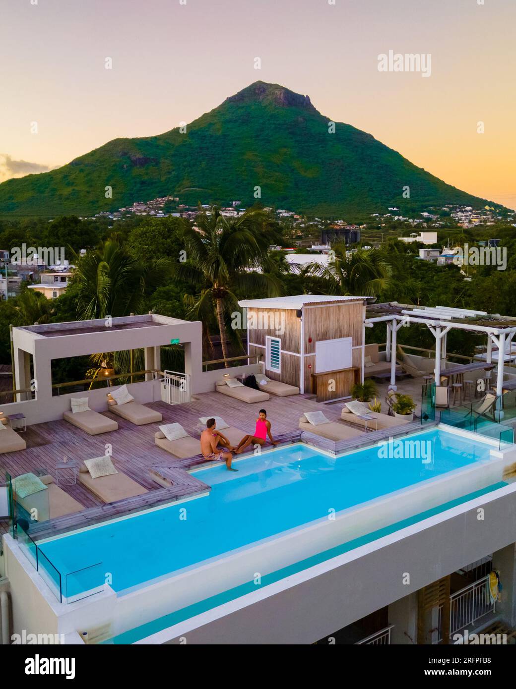 Man and Woman relaxing in a swimming pool watching sunset, a couple on a honeymoon vacation in ...