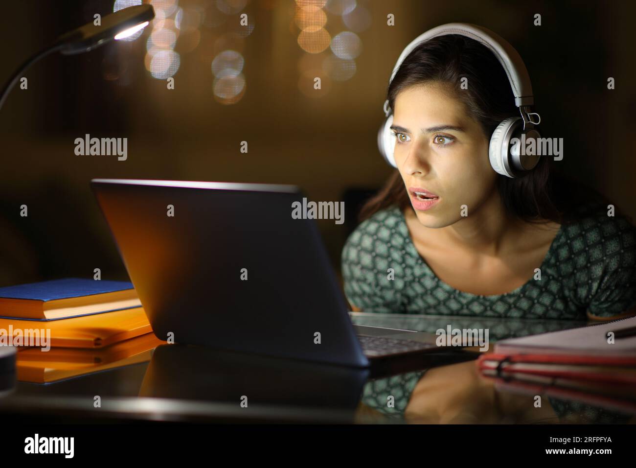 Amazed student e-learning checking laptop content in the night at home ...