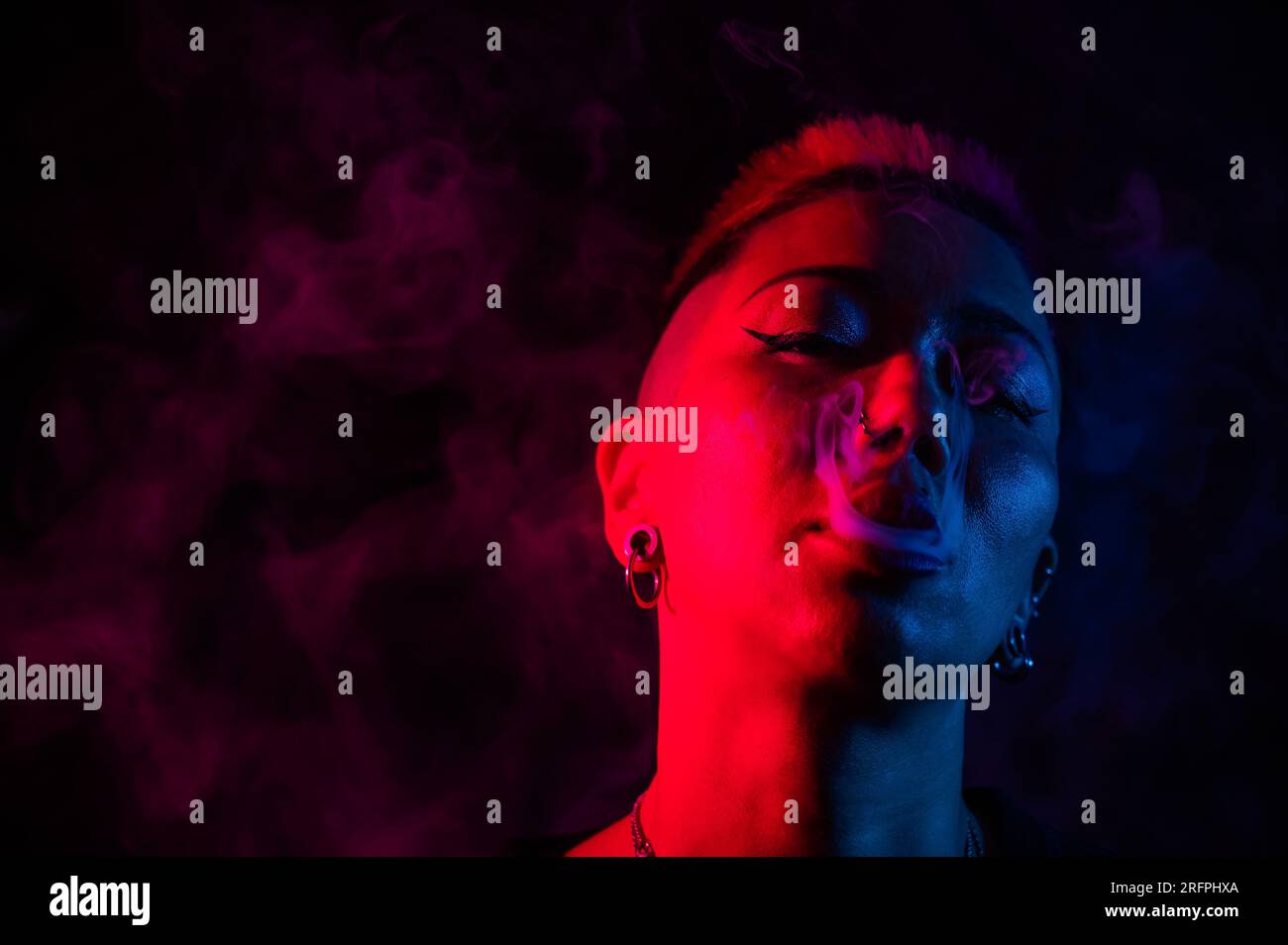 Close up portrait of asian woman with short hair smoking in neon light ...