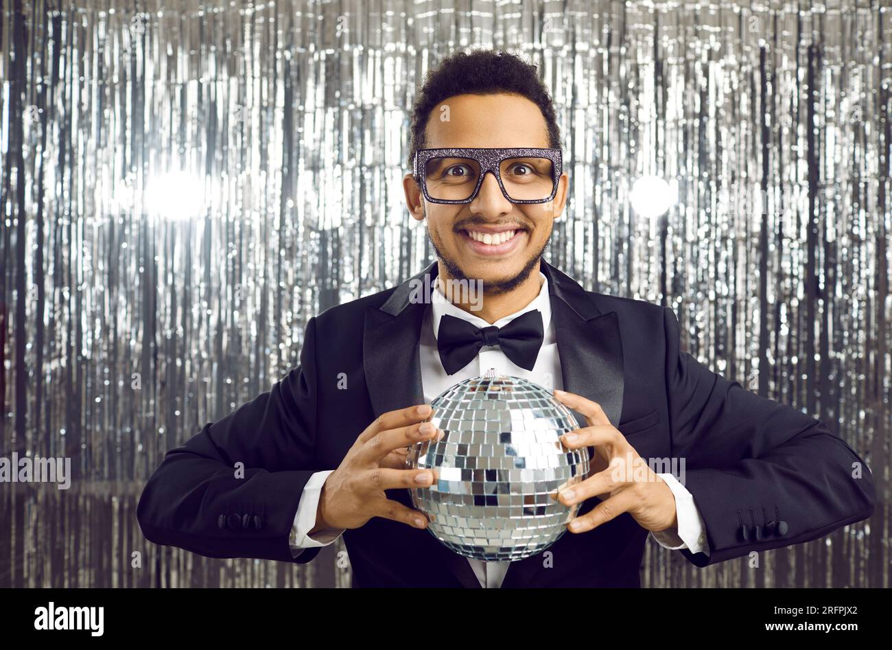Portrait of happy excited young elegant man with disco ball on shiny ...