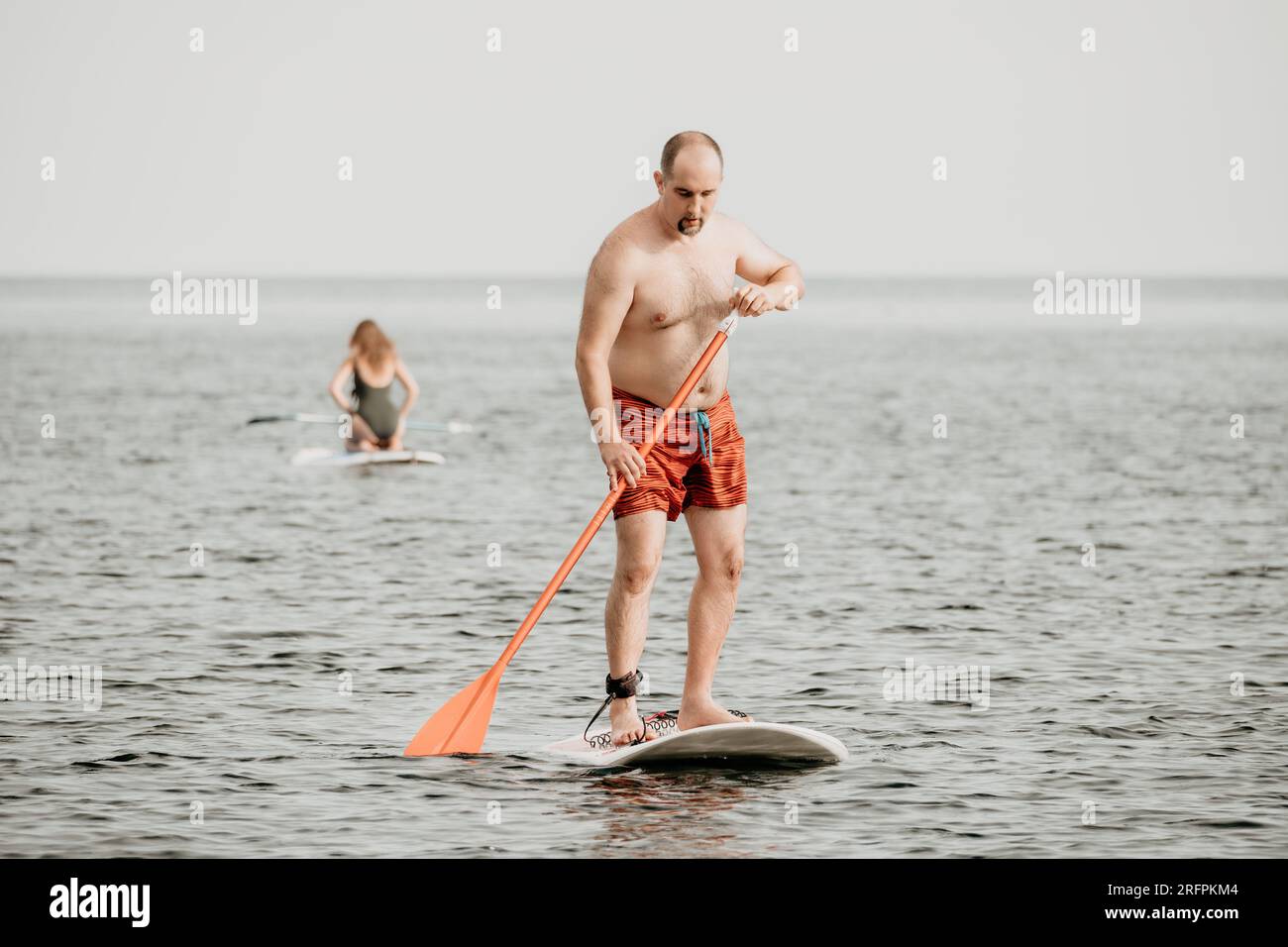 Active mature male paddler with his paddleboard and paddle on a sea at ...