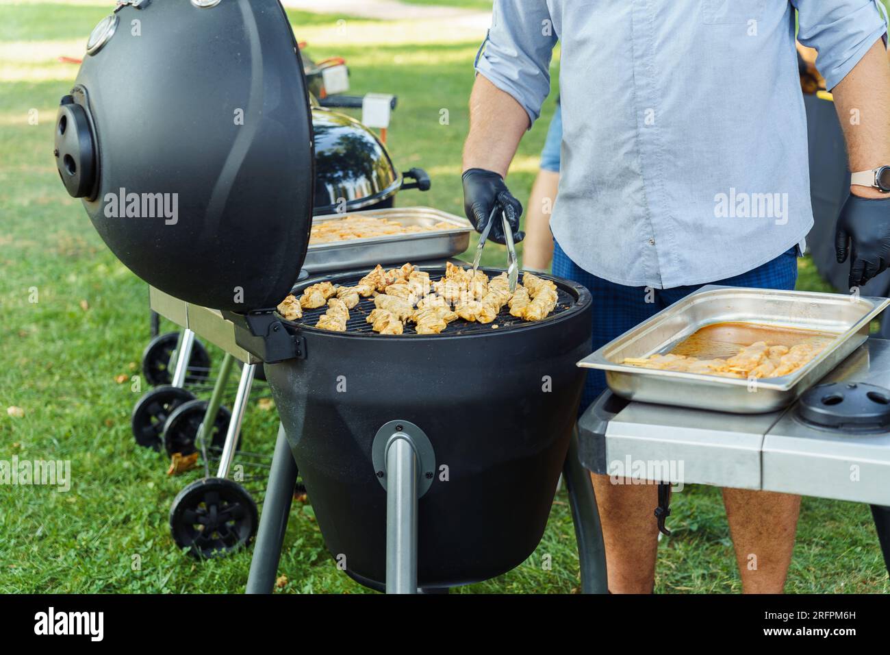 Man grilling chicken during a barbecue party in the garden in the ...