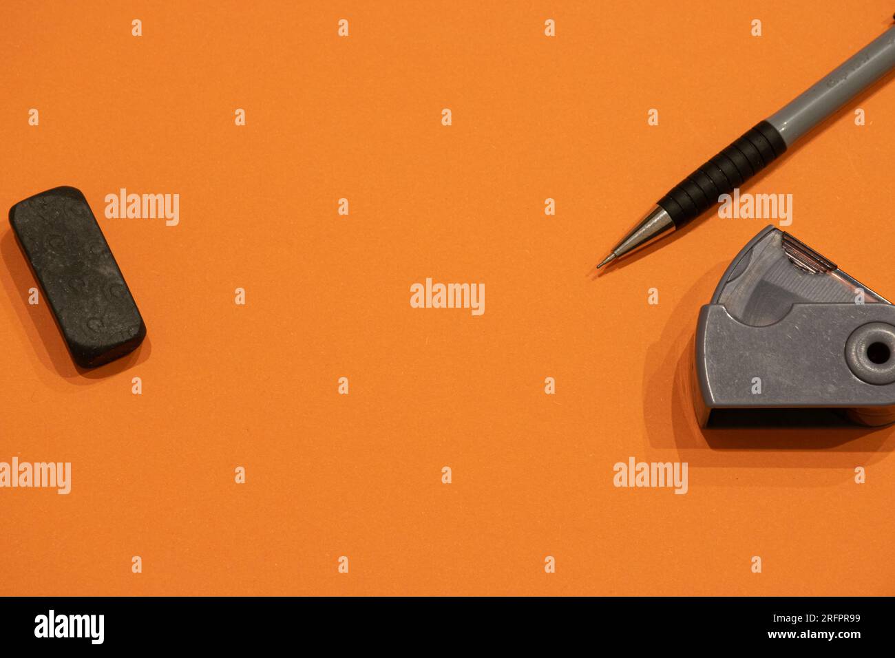 Pencil, pencil sharpener and an eraser isolated on an orange background ...
