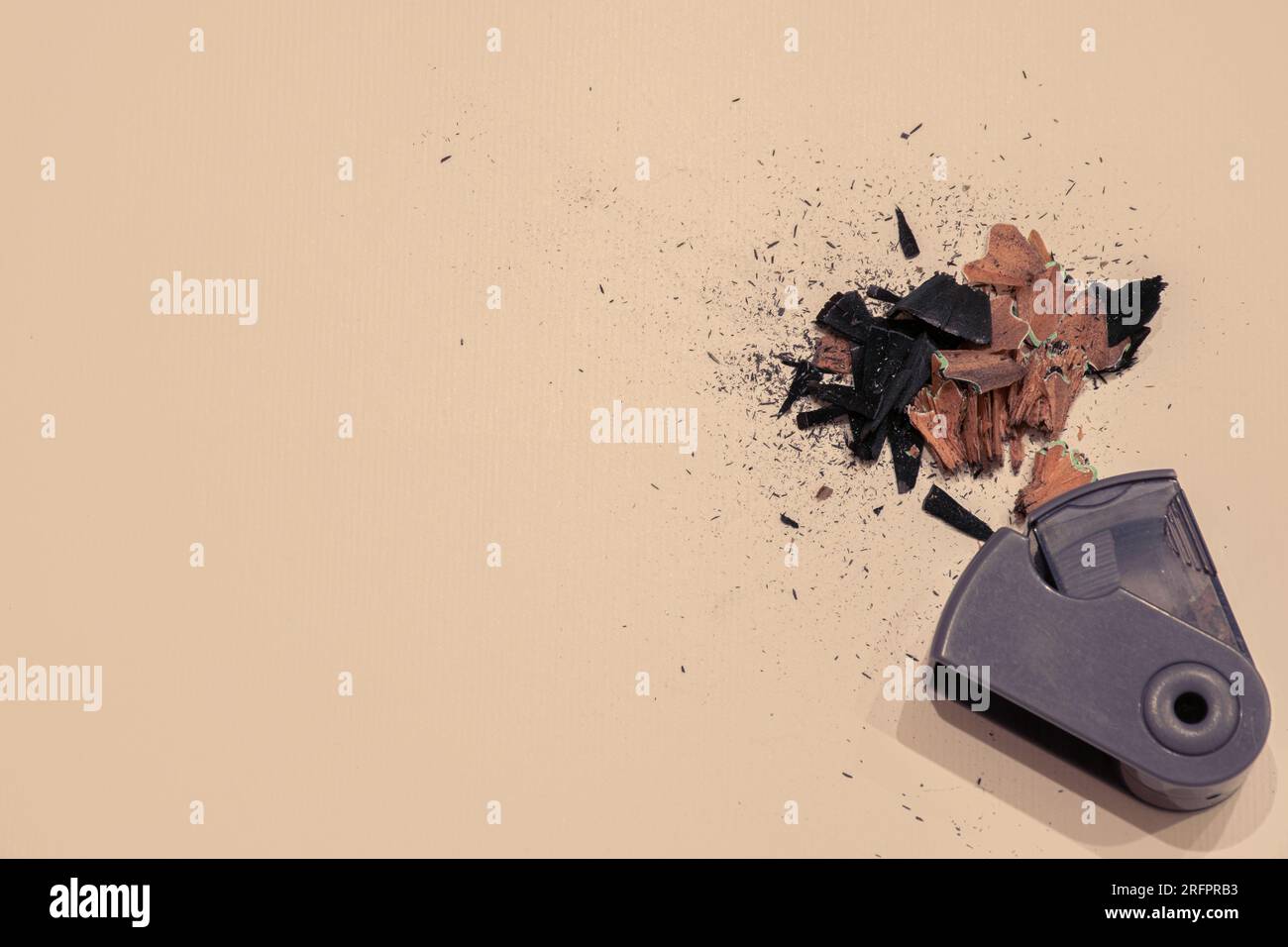 Pencil sharpener and a pile of pencil shavings isolated on a beige ...