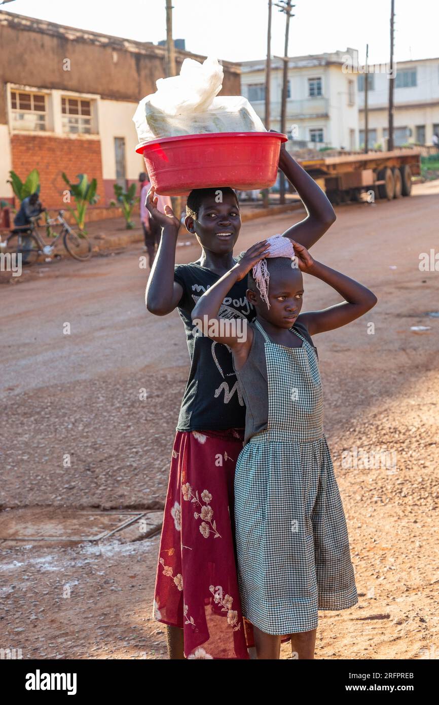 Two young girls carrying on their heads in a street in Jinja, Uganda ...