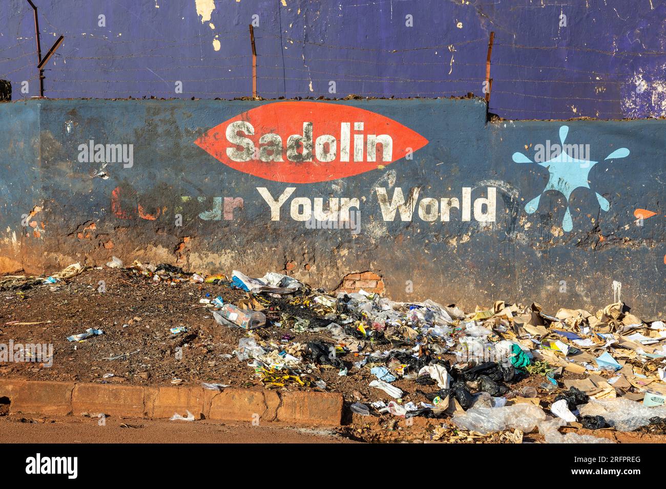 Garbage in front of a "Sadolin color your world" advertisement. Jinja ...