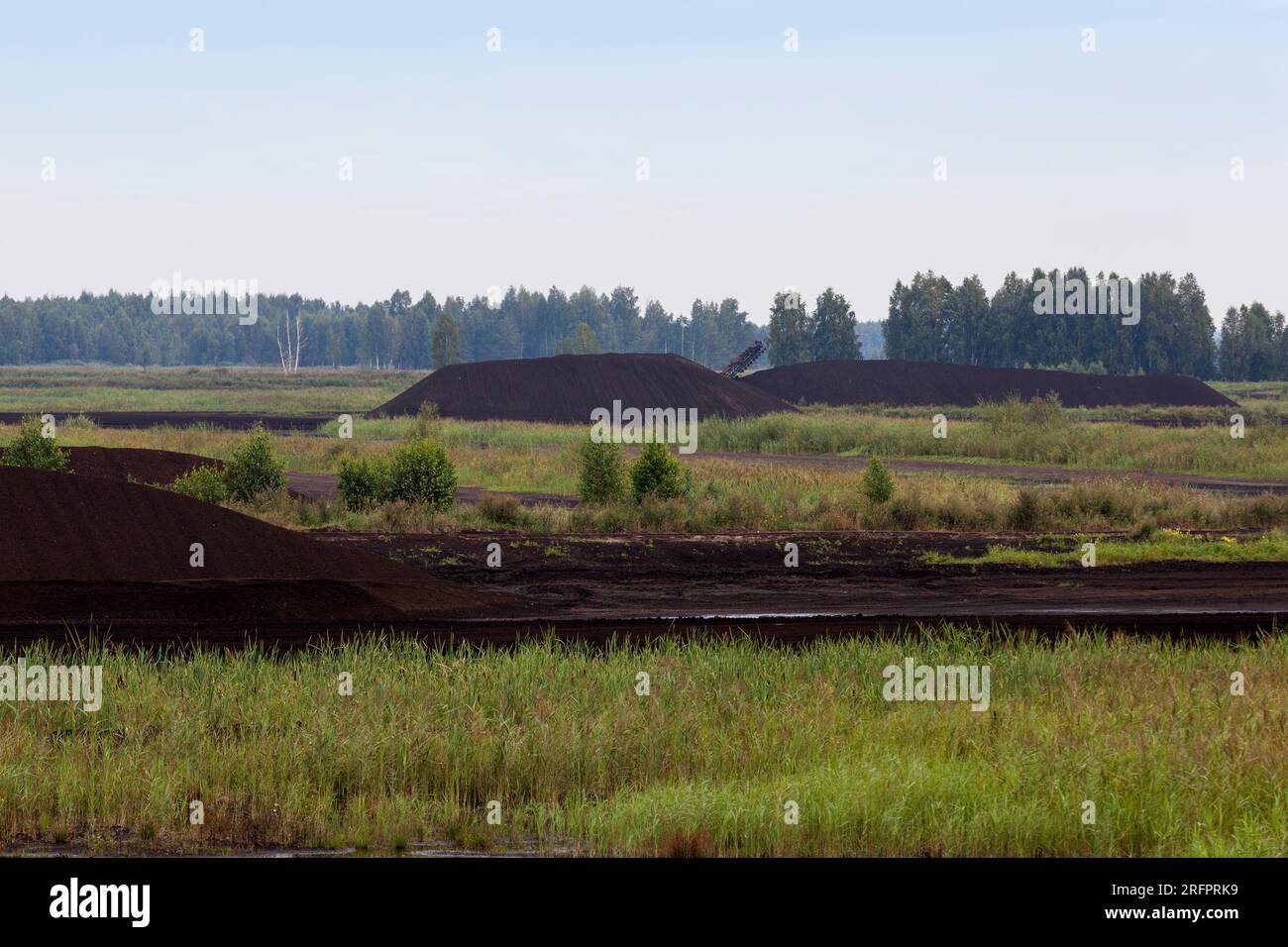 the flooded area where peat is extracted, black peat is stacked in huge ...