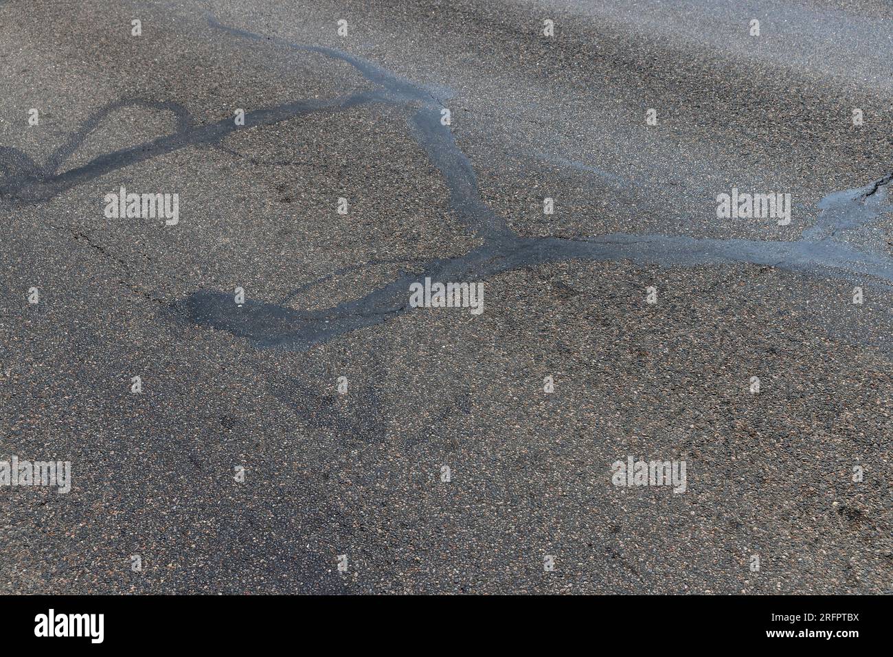 Repaired asphalt road in close up, paved road with traces of repair and ...