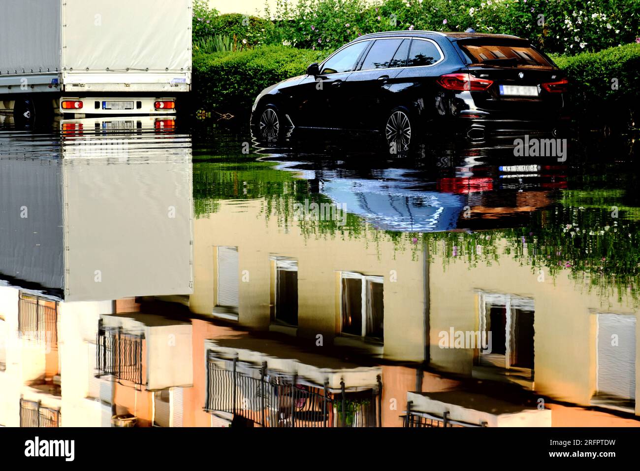 urban street scene after heavy storm. flooded road. car partly in deep ...