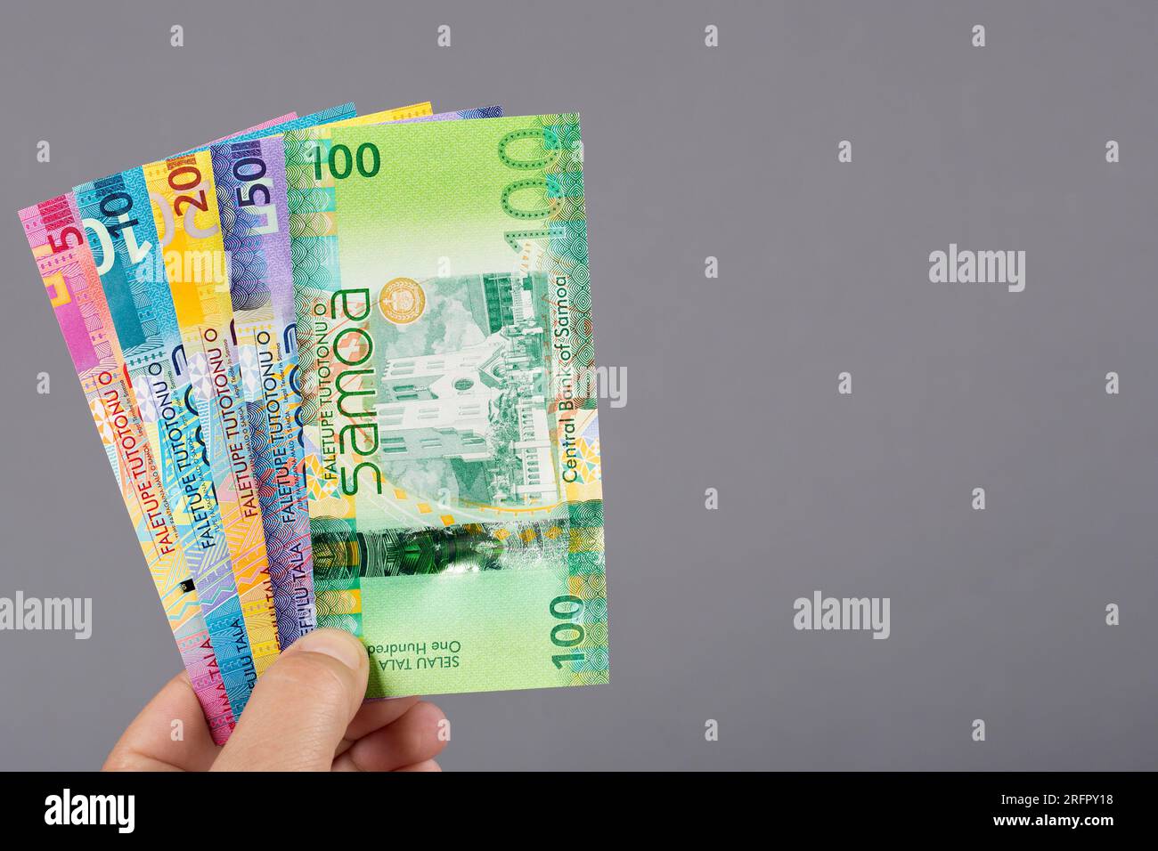Samoan money - tala in the hand on a gray background Stock Photo - Alamy