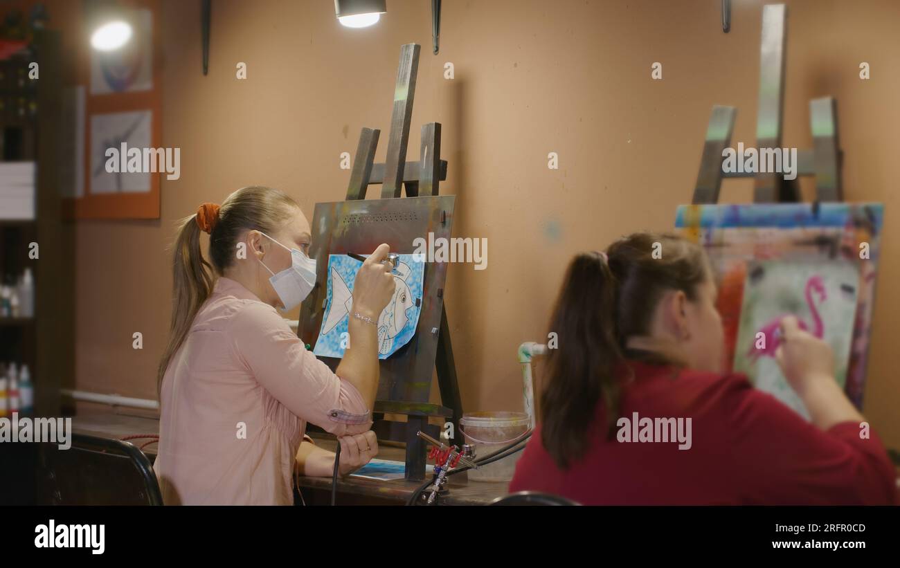 Woman artist learns to paint with airbrush with acrylic dye, paper and ...