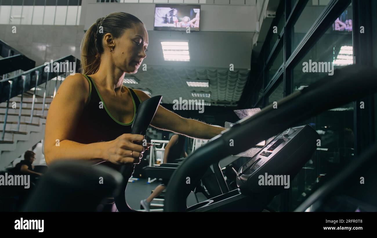 Fit Athletic Woman Exercising on an Elliptical Machine. Muscular Women ...