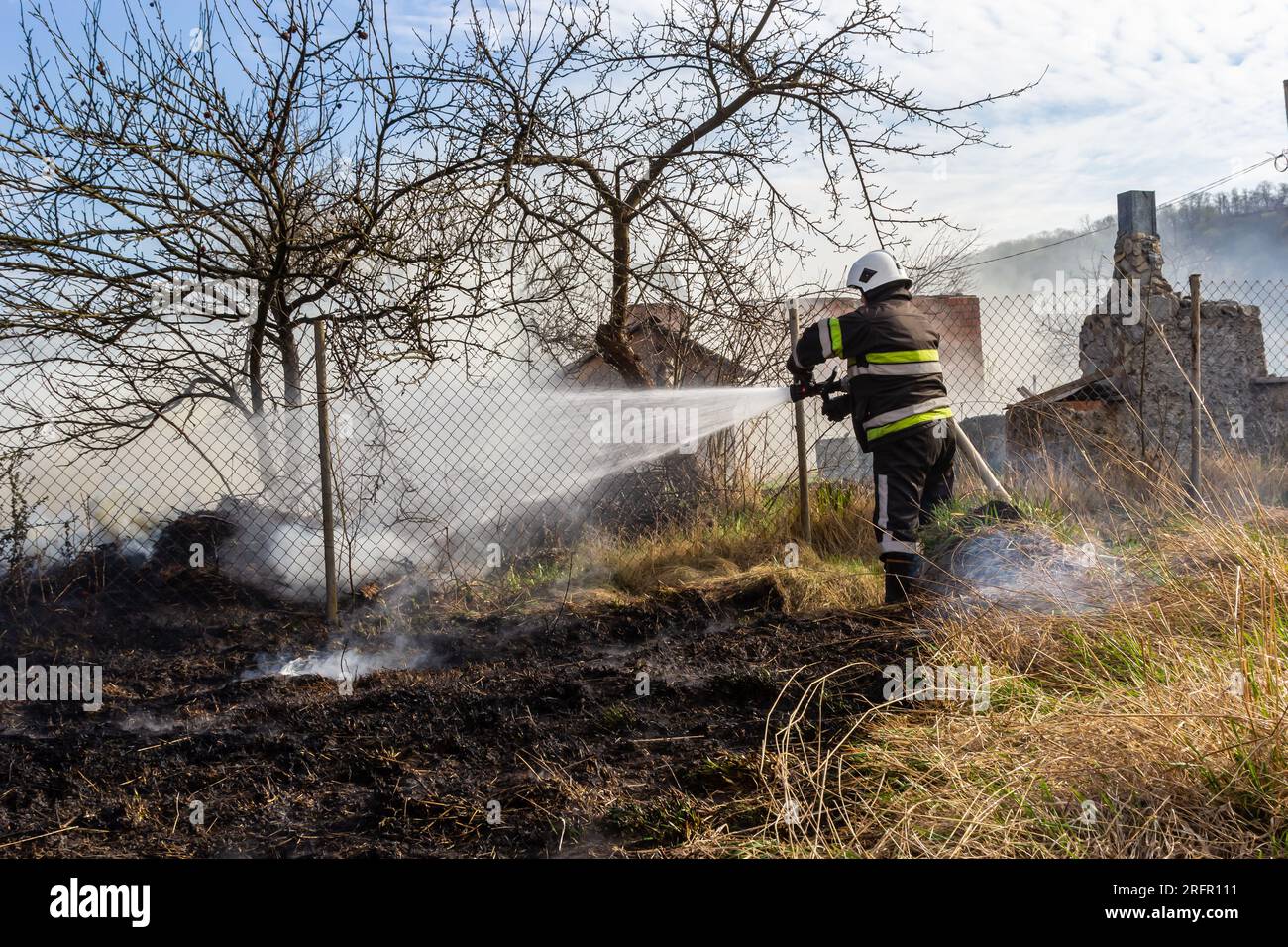 spring fire, burning dry grass near buildings in the countryside ...