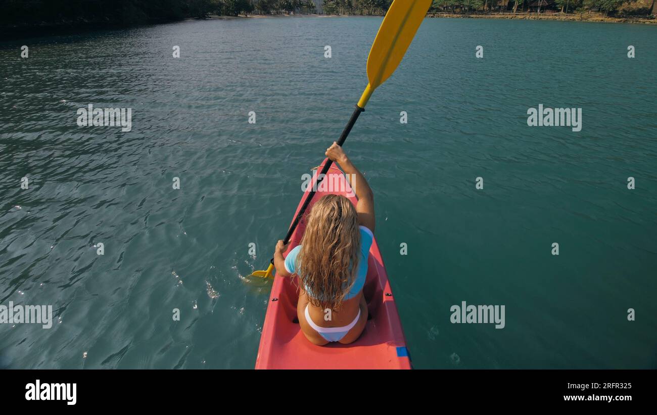 Seductive blonde woman in blue swimsuit sails on pink plastic kayak ...