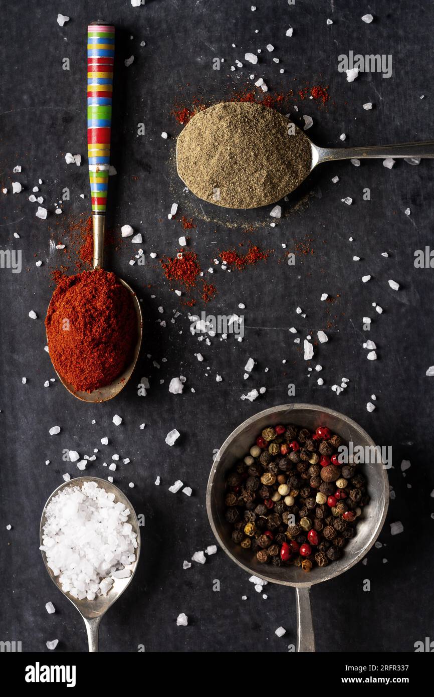 Old spoons with peppercorn, ground pepper, salt and red paprika powder ...
