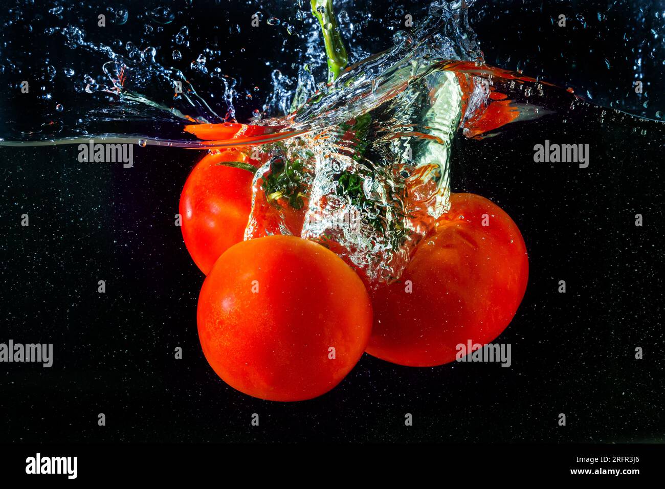 Fresh red tomato falling into water with water splash and air bubbles ...