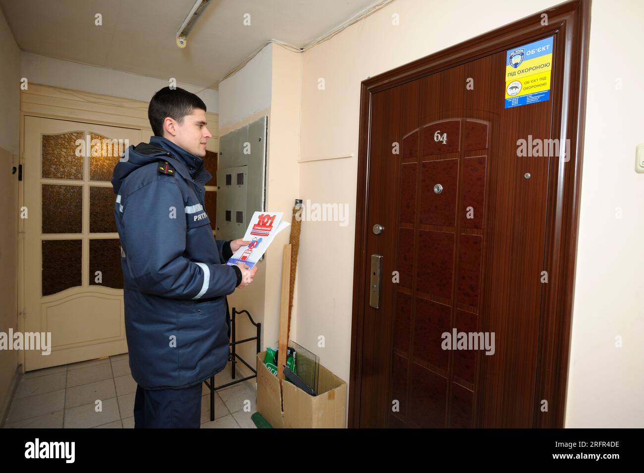 Fireman officer stands by the door of an apartment with brochure in ...