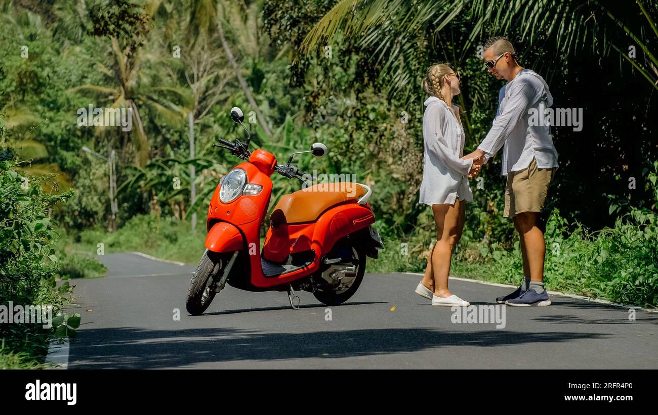 Two caucasian tourist woman man dance near scooter. Love couple on red ...