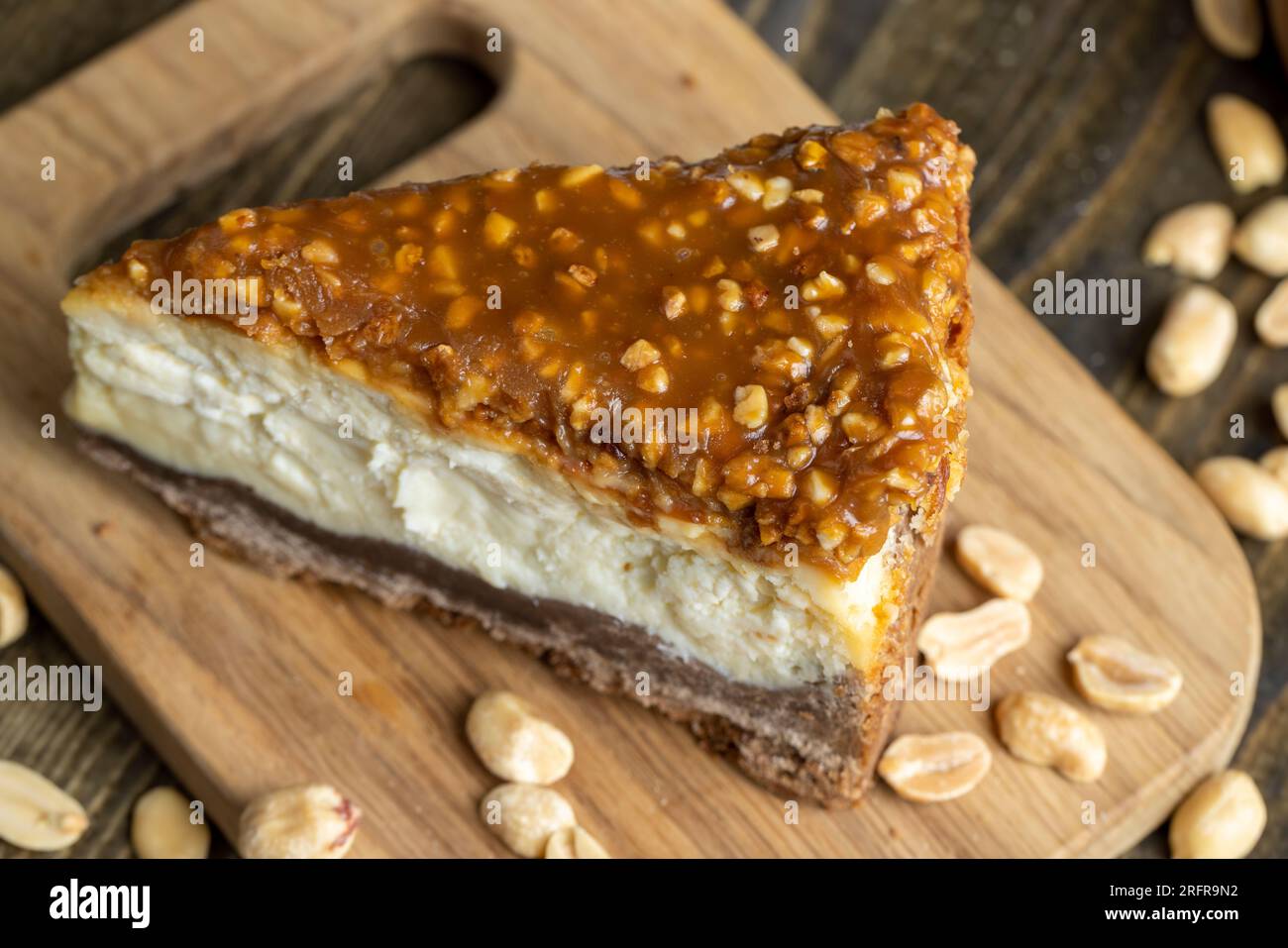 Cheesecake made of soft fresh cheese and peanuts in salted caramel, sweet combined dessert cut ...