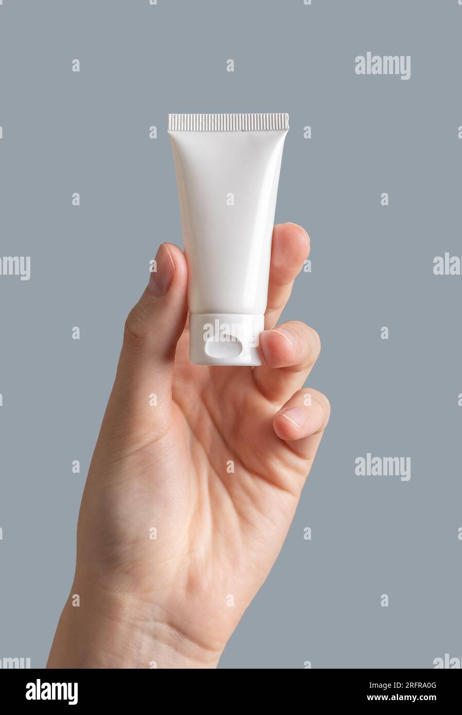 Hand holding small cream tube mock up, blank white package for little ...