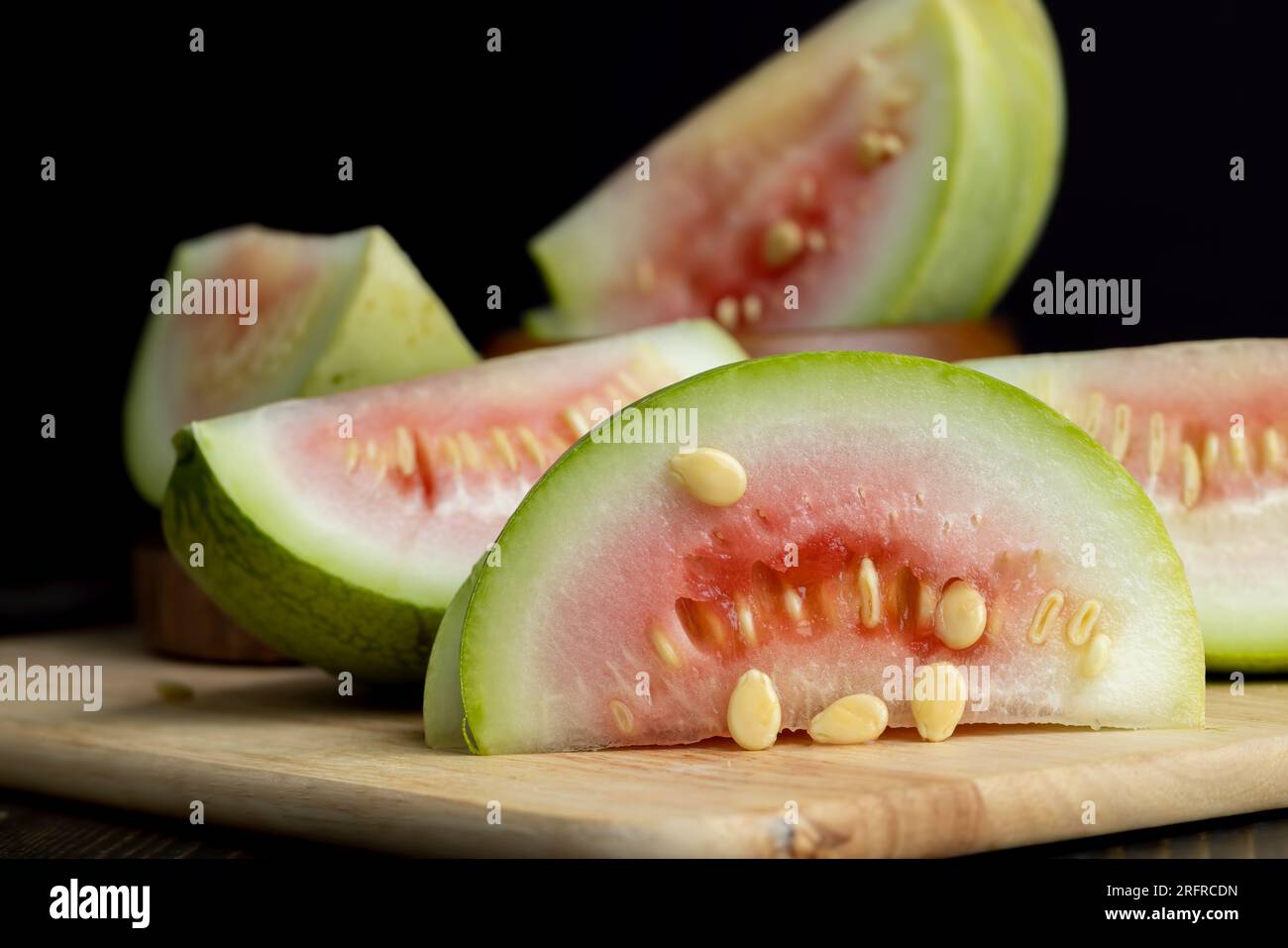 cut small unripe watermelon on a board, cut into pieces unripe ...