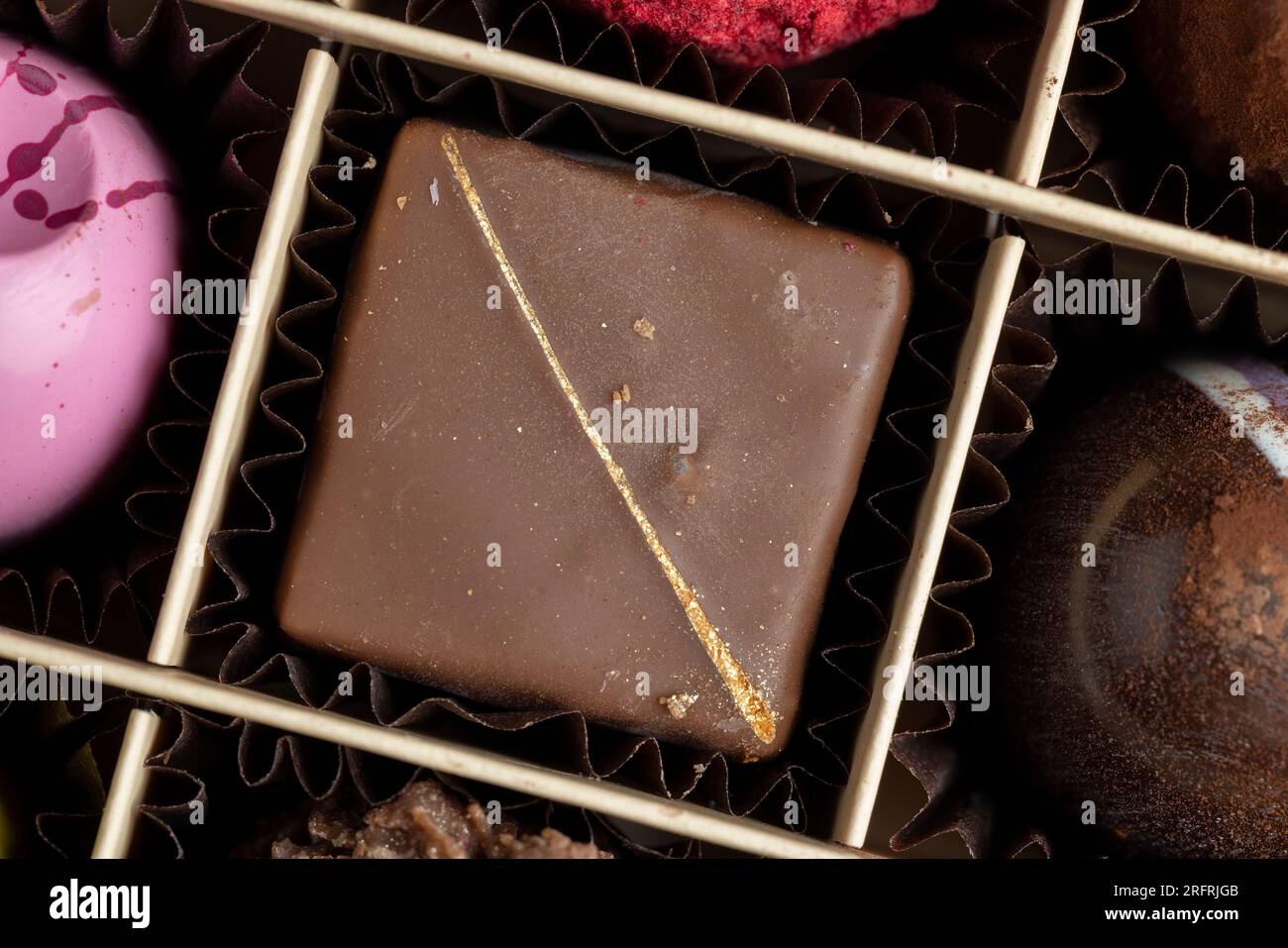 Different chocolates without packaging lying on a wooden board ...