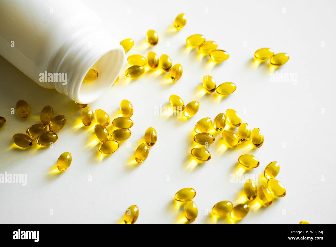 Close up vitamin D3 softgel capsules on a white surface. Yellow ...