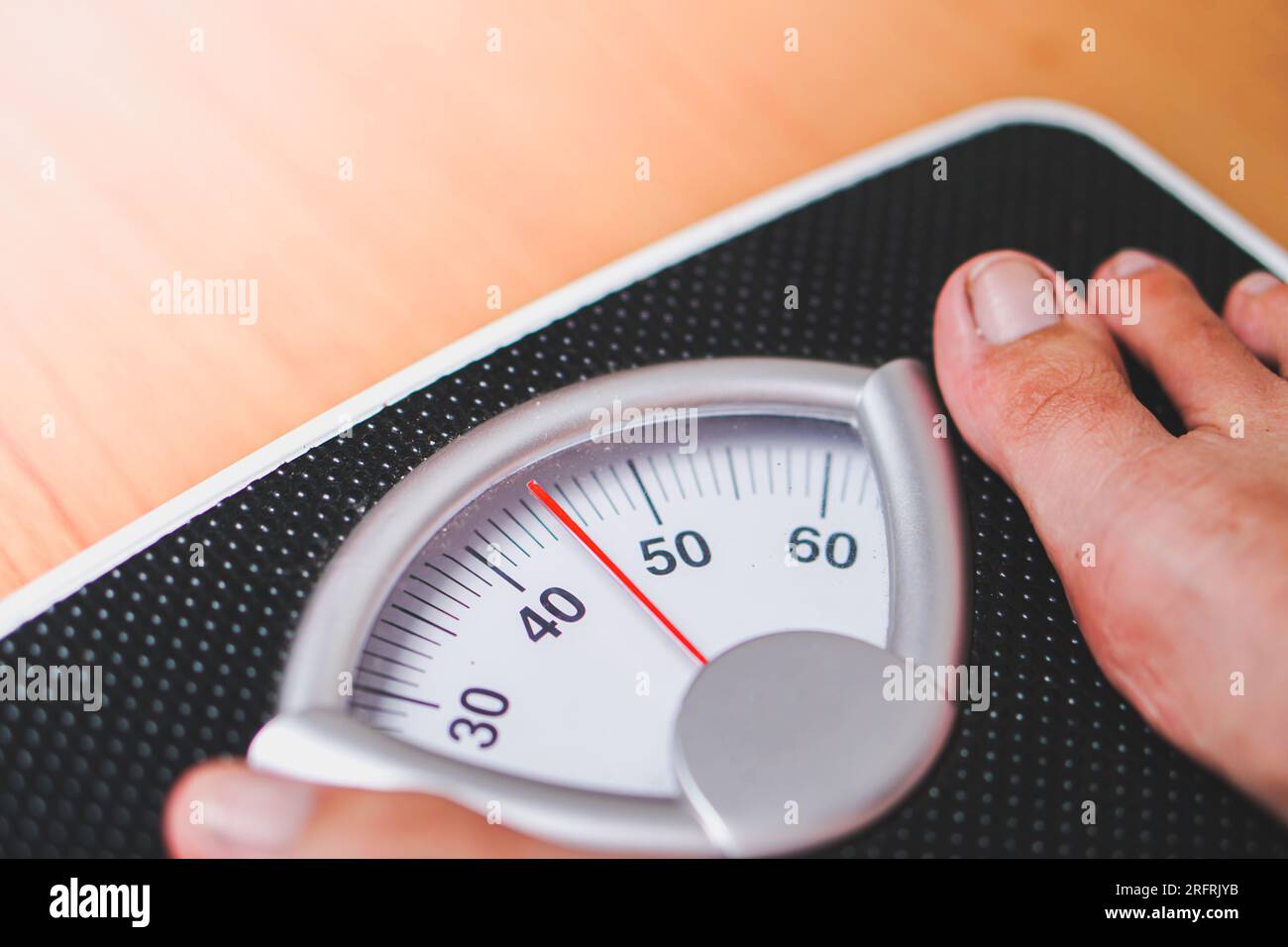 feet standing on a black scale weighing machine with a wooden base ...
