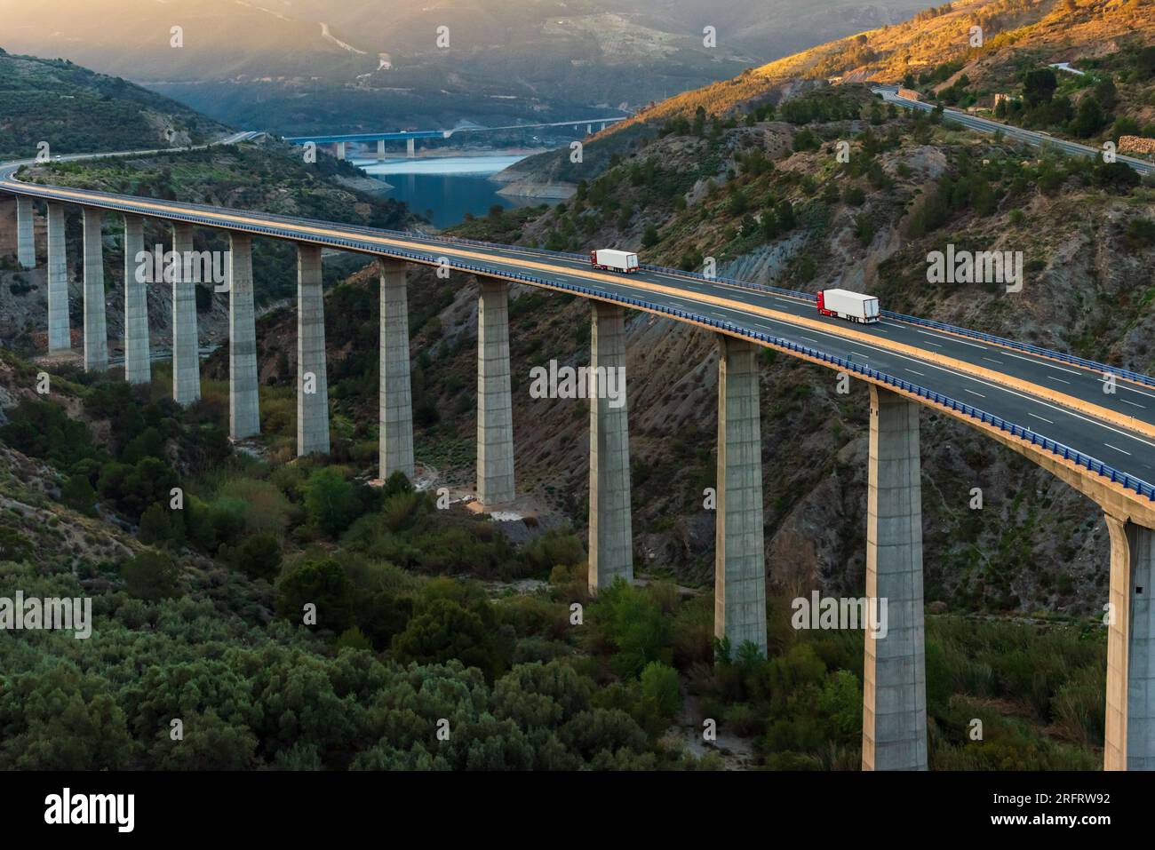 Two trucks with refrigerated trailers driving on a very long and high ...