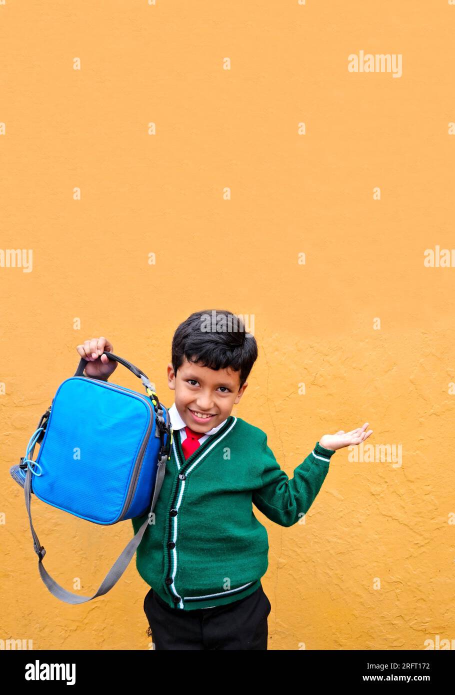 Dark-haired 9-year-old Latino boy in a school uniform shows off his new ...